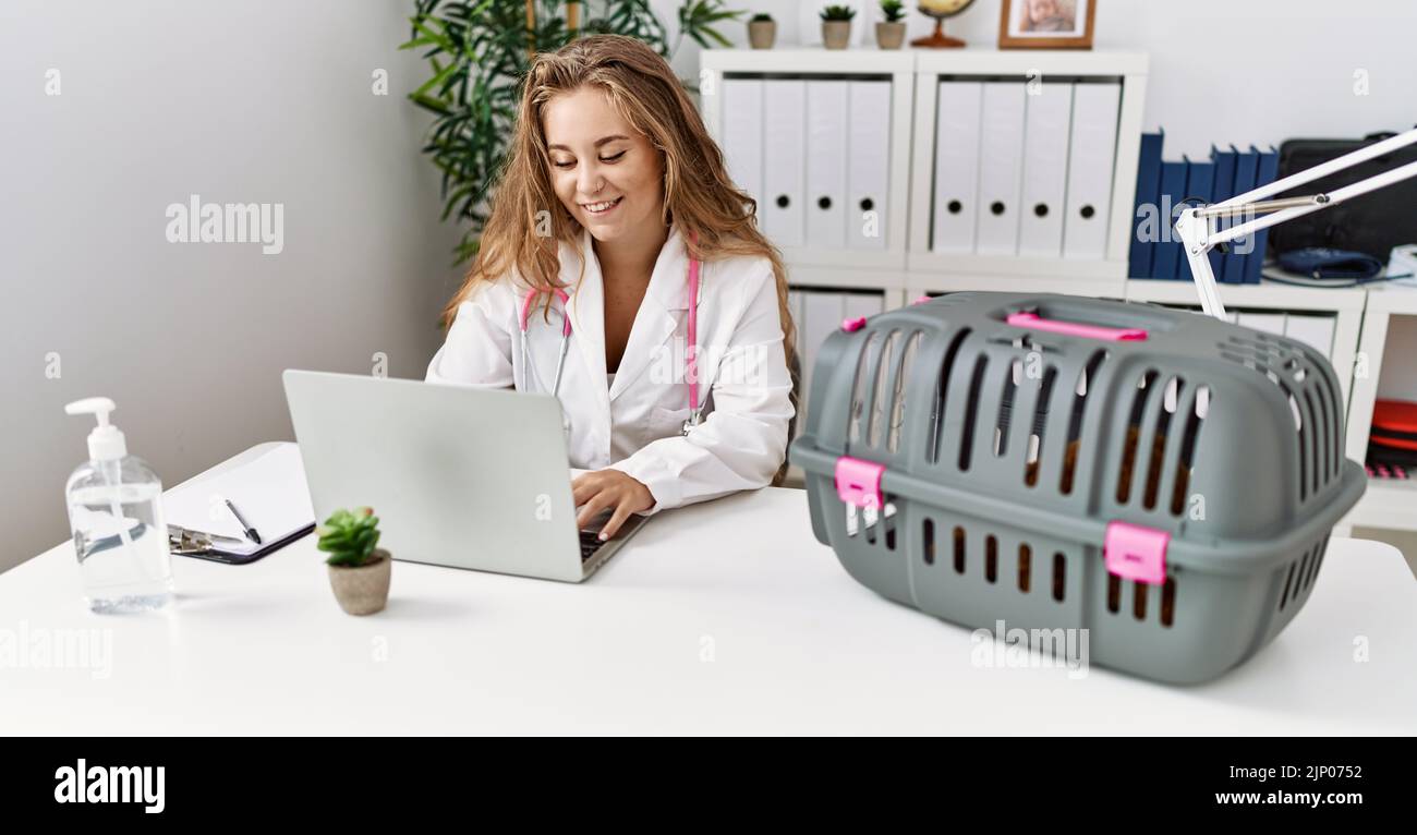 Young blonde girl wearing veterinarian uniform working at veterinary ...