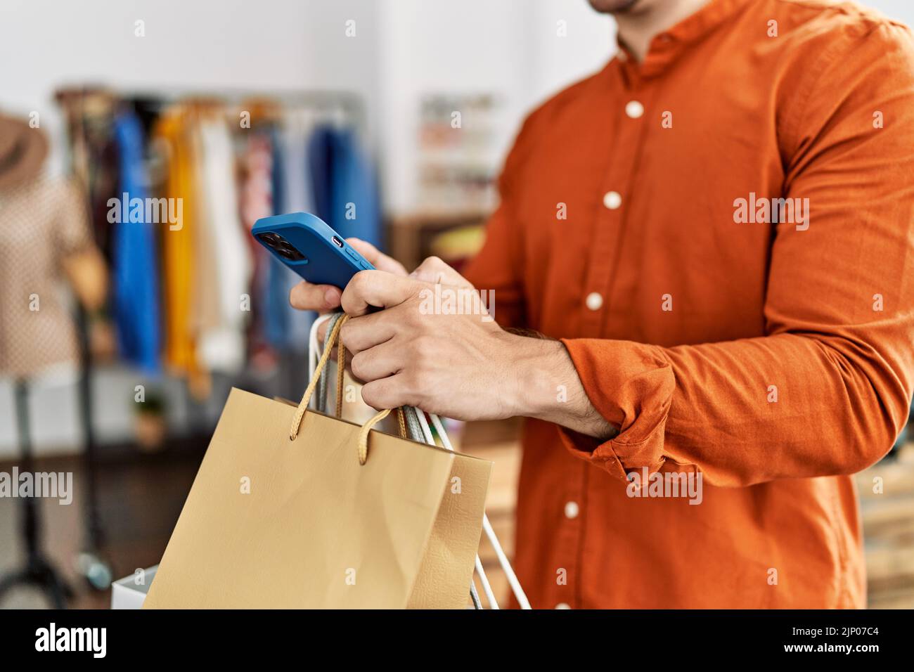Customer man holding shopping bags and using smartphone at clothing ...