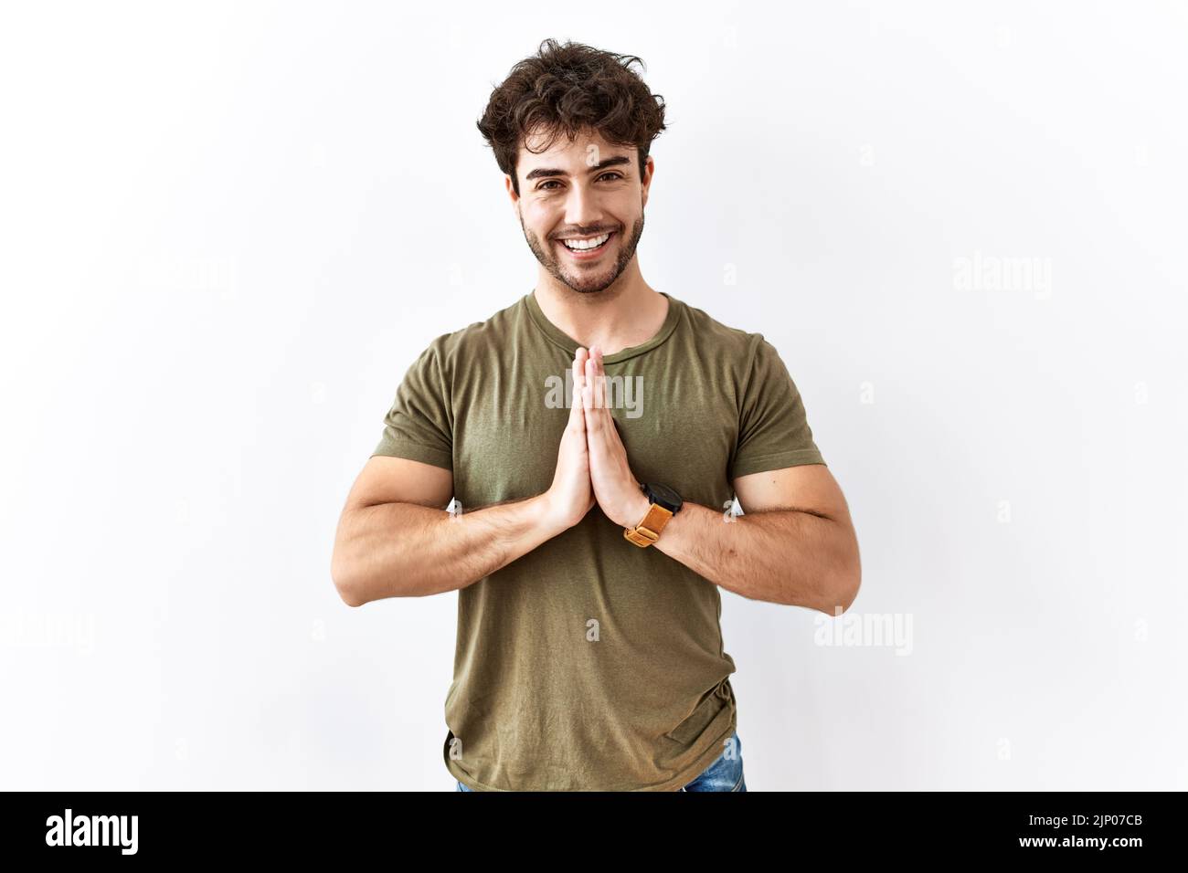 Hispanic man standing over isolated white background praying with hands ...