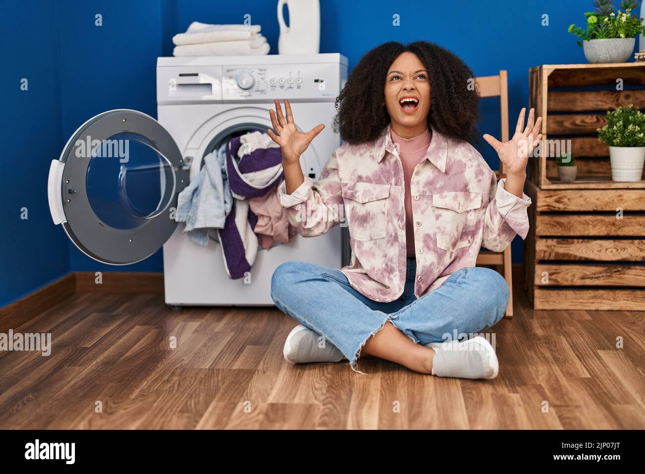 Young african american woman sitting on the floor doing laundry crazy ...