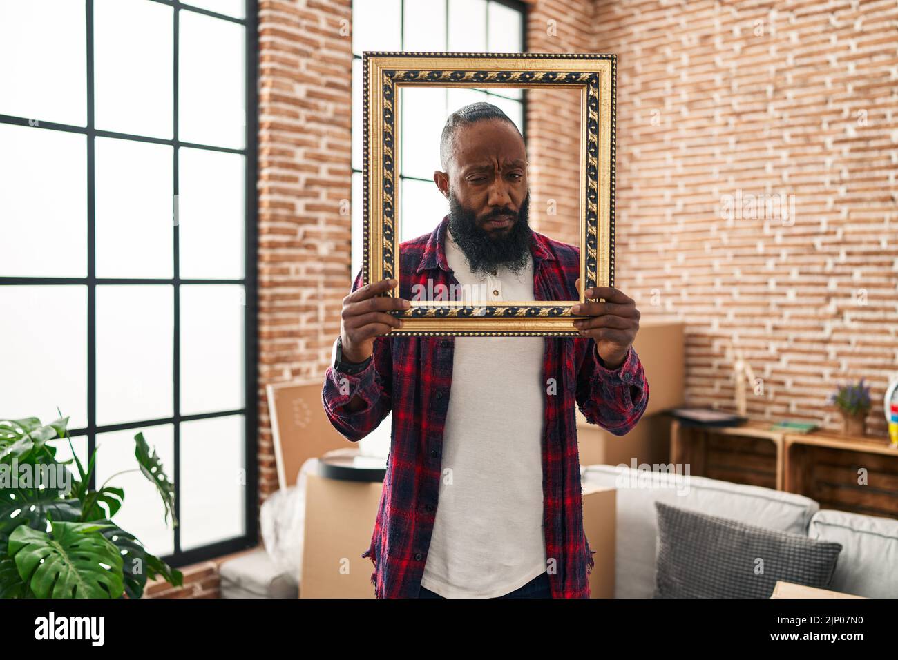 African american man putting face in empty frame skeptic and nervous ...