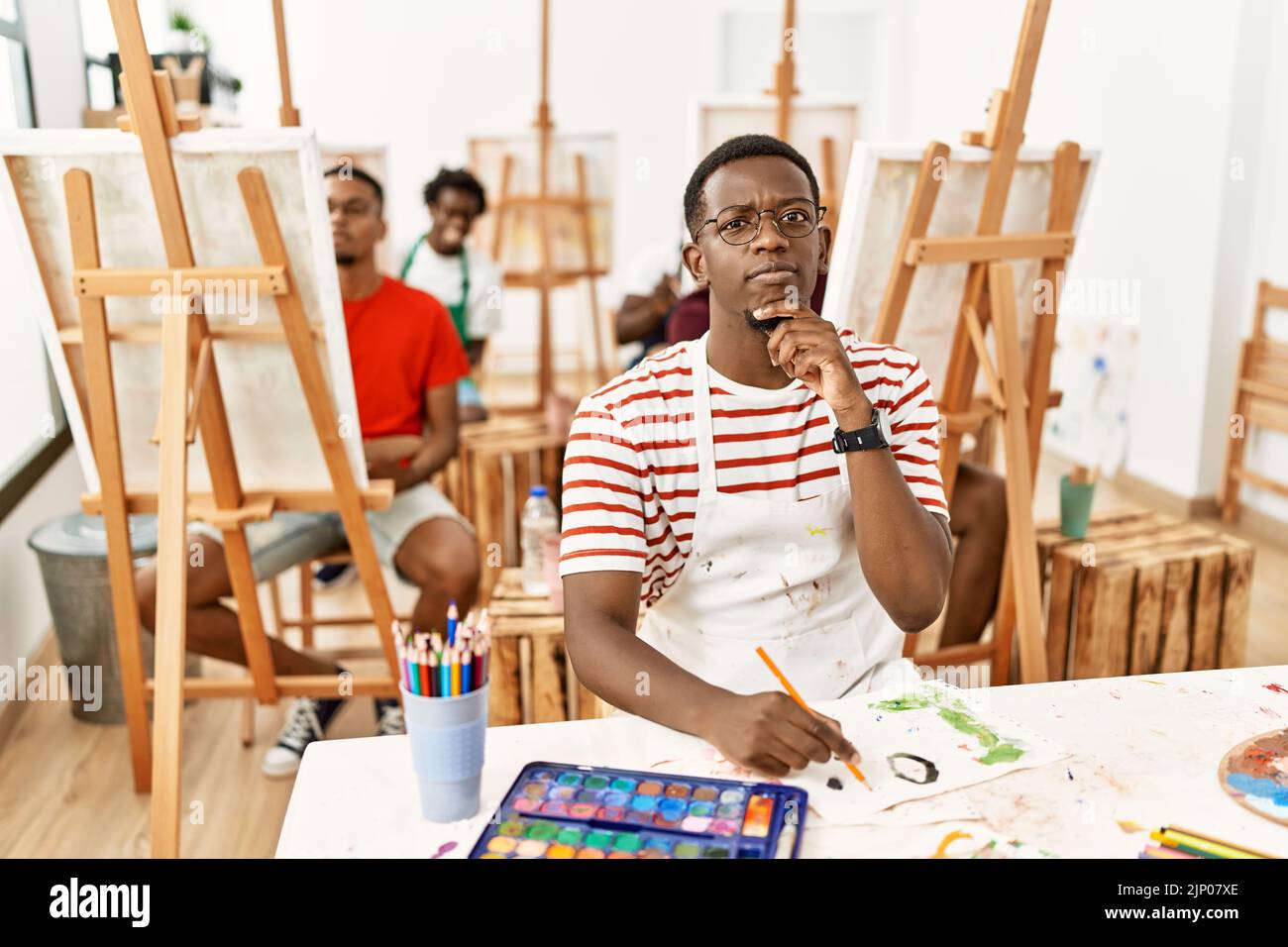 Young african man at art studio serious face thinking about question ...