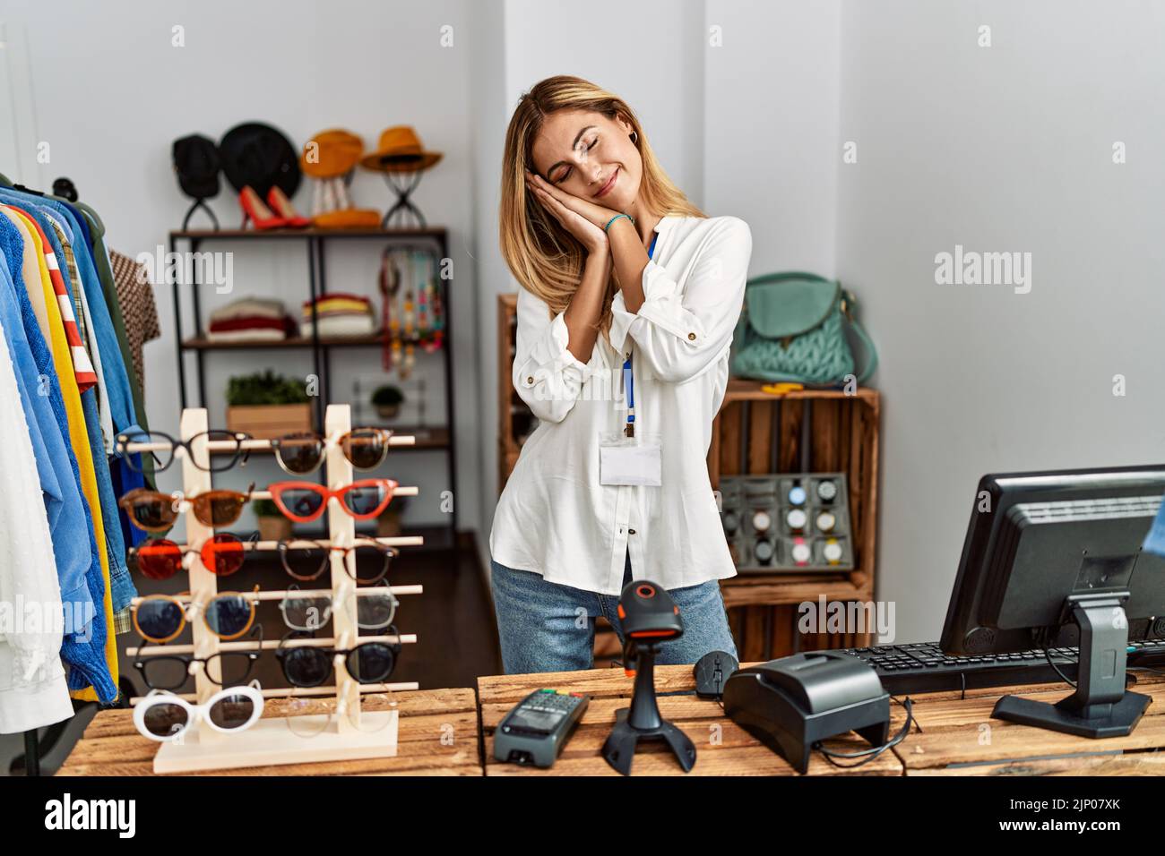 Blonde beautiful young woman working as manager at retail boutique sleeping tired dreaming and ...