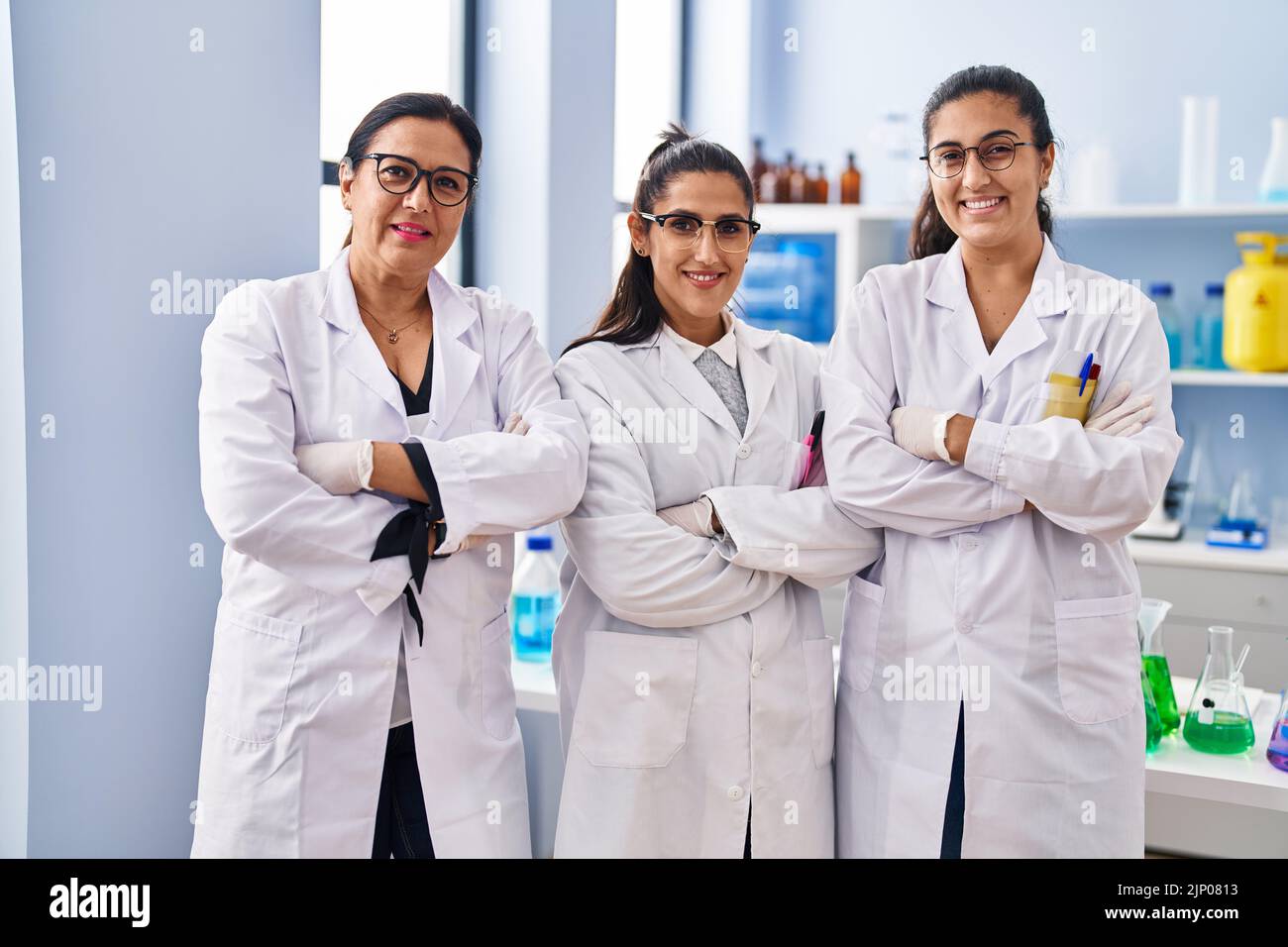 Three woman scientists standing with arms crossed gesture at laboratory ...