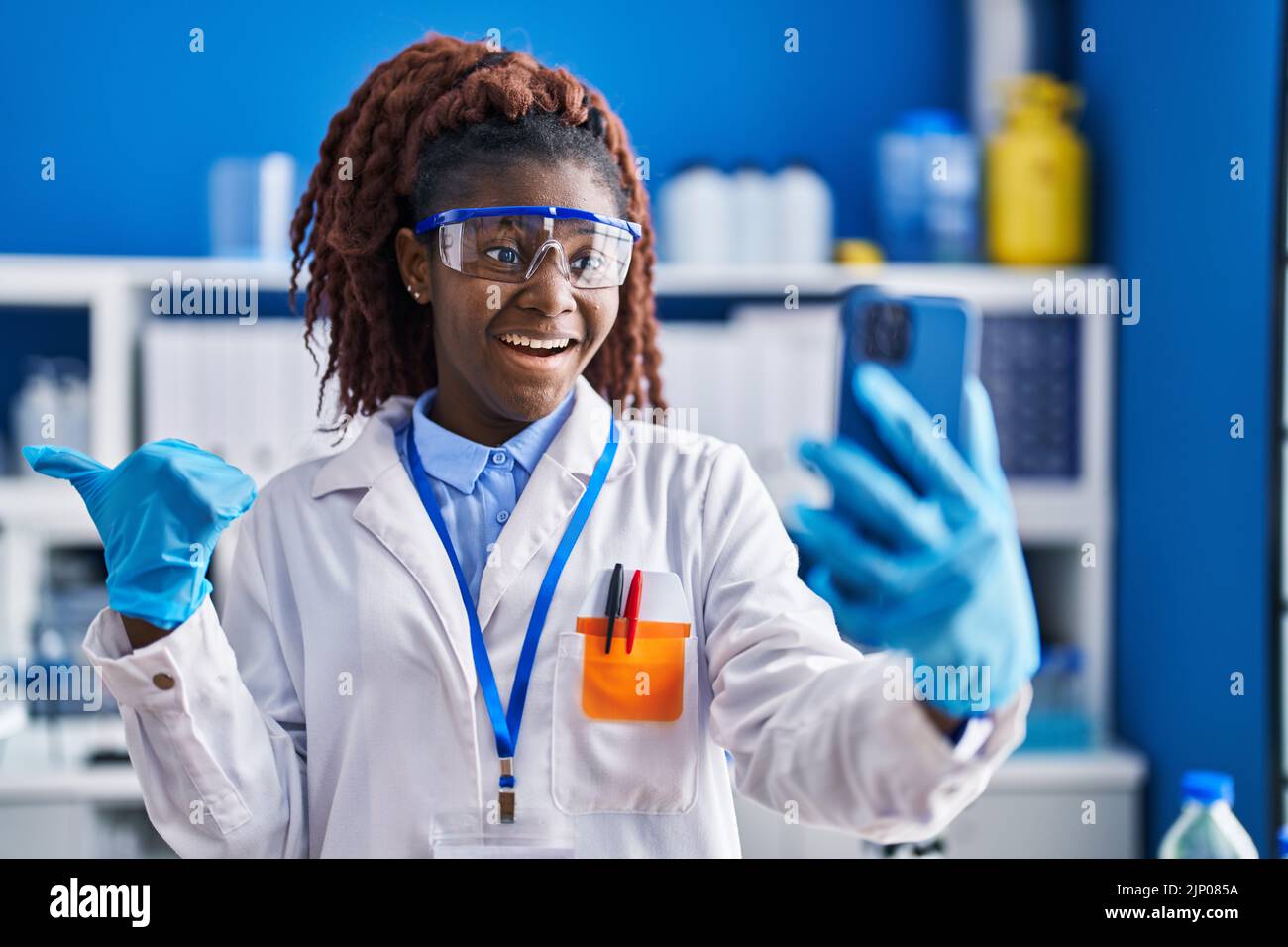 African woman working at scientist laboratory doing video call pointing ...
