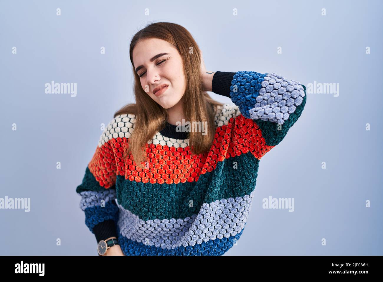 Young hispanic girl standing over blue background suffering of neck ...