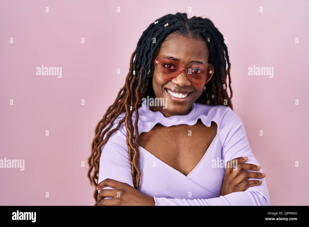 African woman with braided hair standing over pink background happy ...