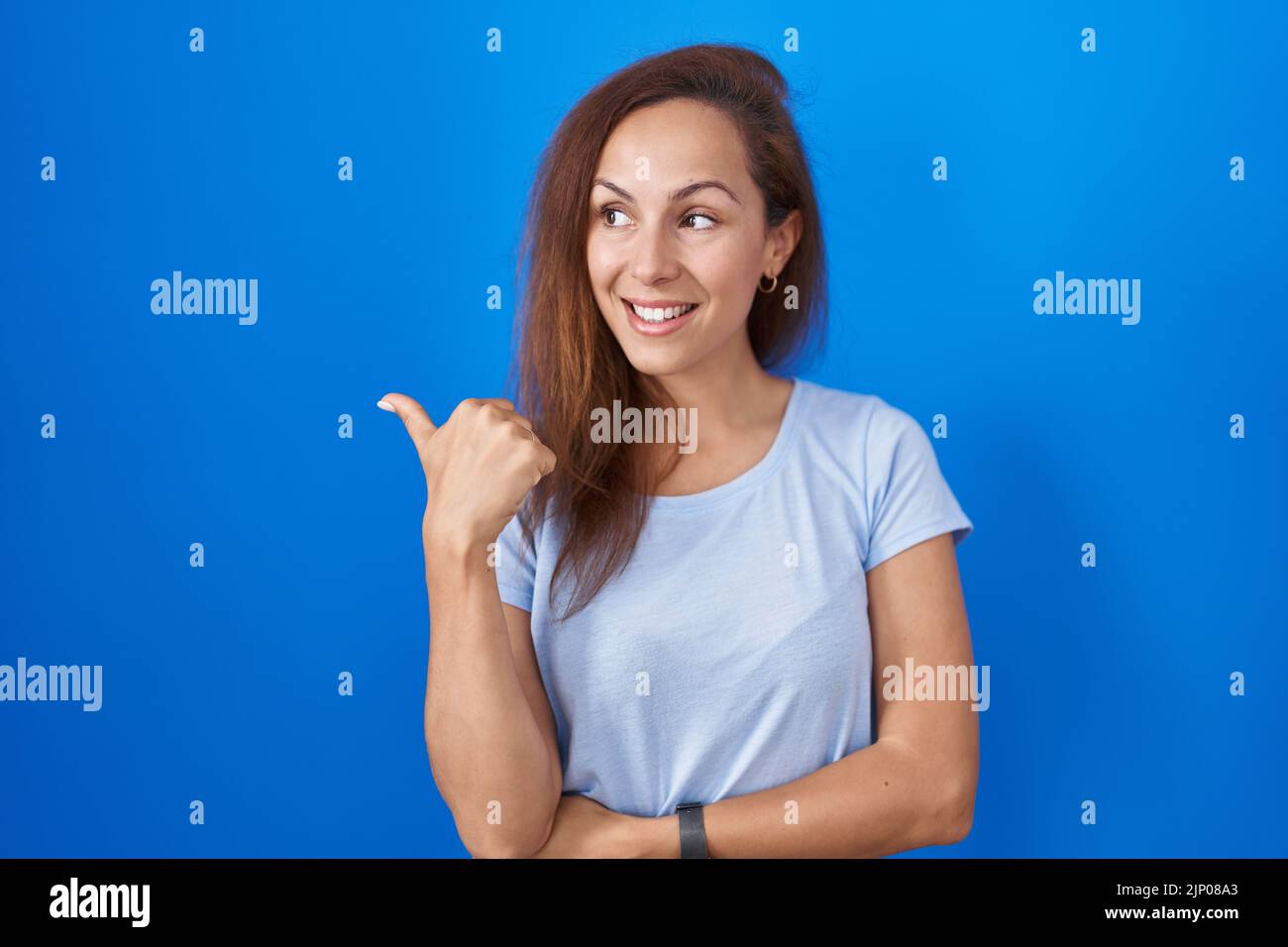 Brunette woman standing over blue background smiling with happy face ...