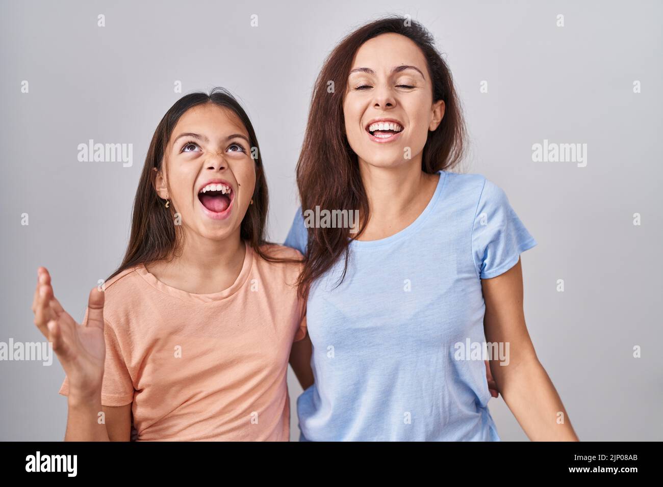 Young mother and daughter standing over white background crazy and mad ...