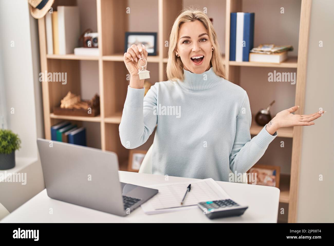 Young caucasian woman holding keys of new home celebrating achievement ...