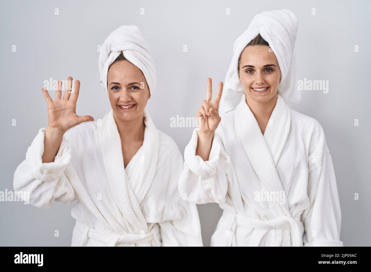 Middle age woman and daughter wearing white bathrobe and towel showing ...