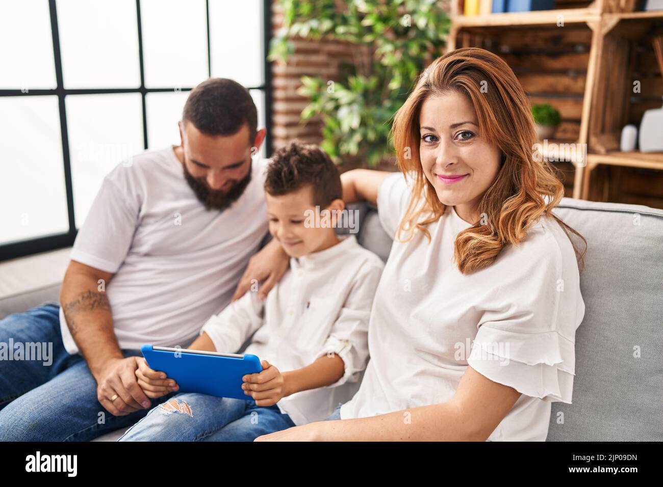 Family using touchpad hugging each other sitting on sofa at home Stock ...