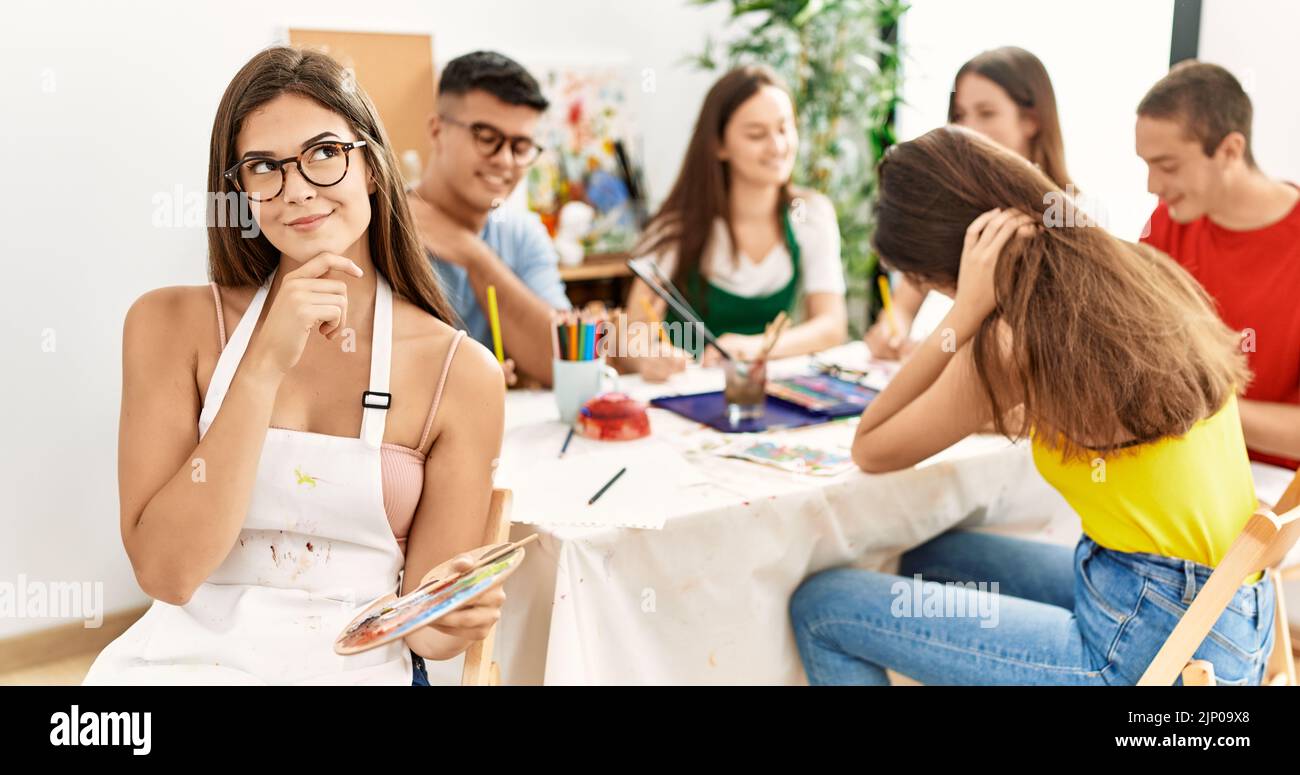 Young artist woman drawing at art studio serious face thinking about ...