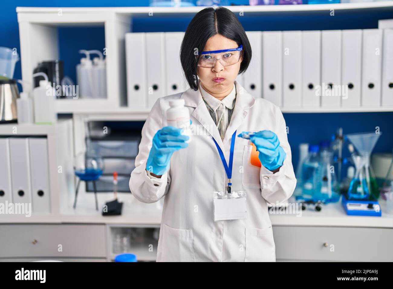 Young asian woman working at scientist laboratory skeptic and nervous ...