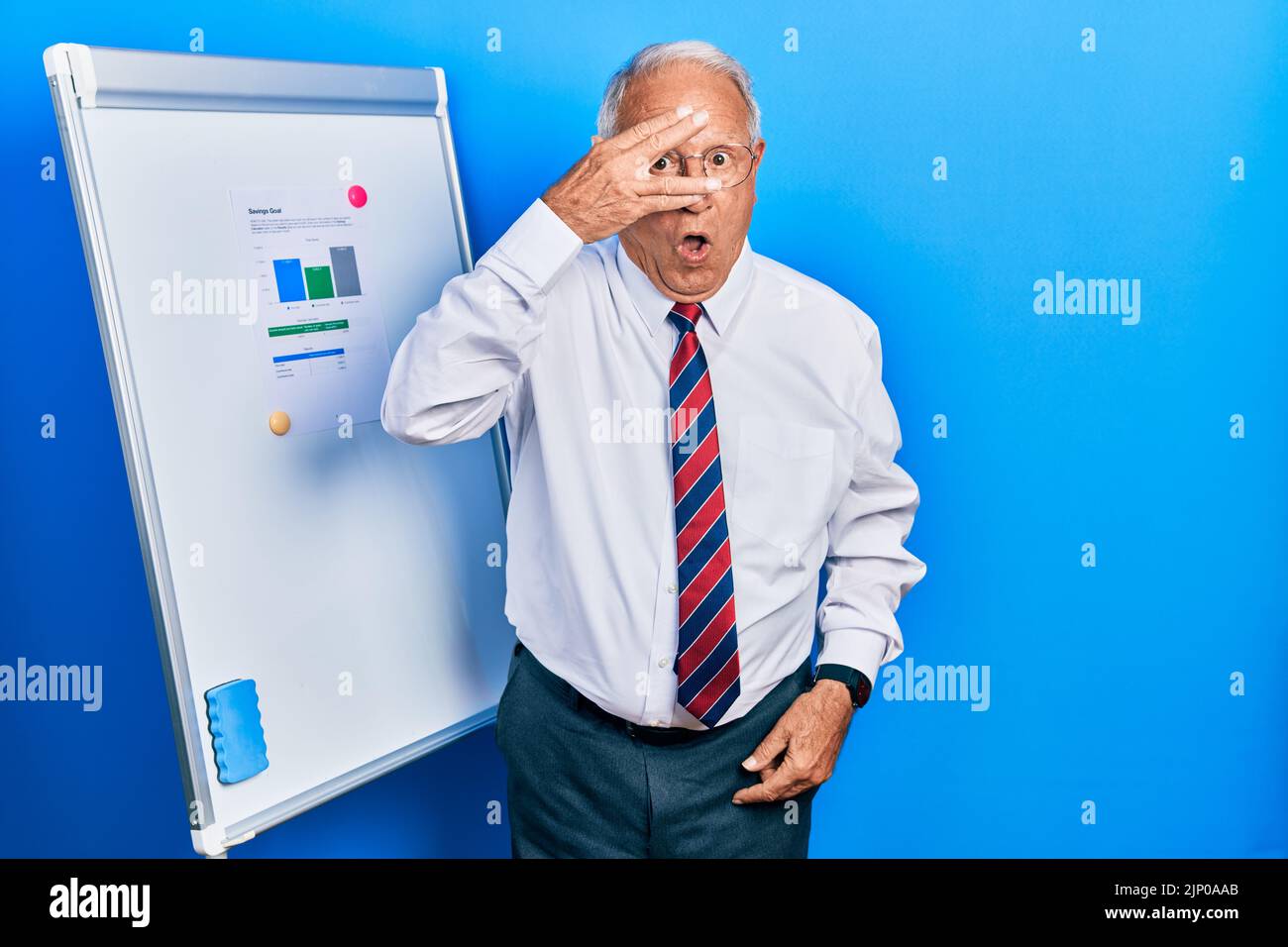 Senior man with grey hair standing by business blackboard peeking in ...