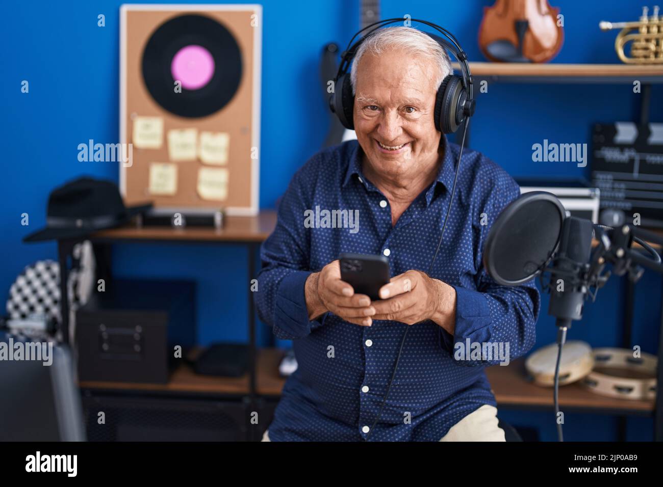 Senior grey-haired man artist listening to music using smartphone at ...