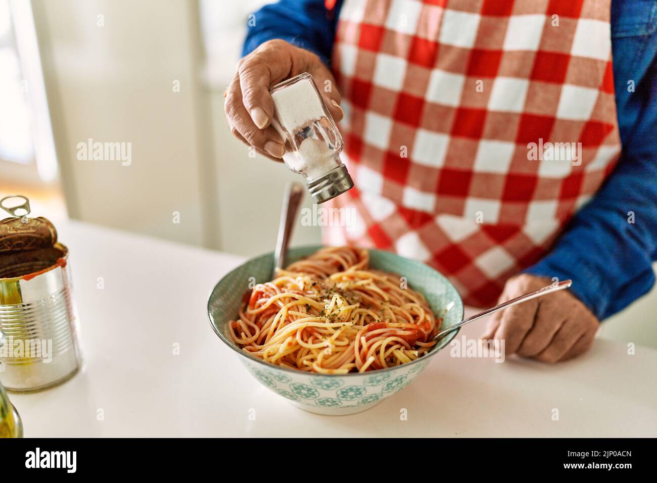 Senior man pouring salt on spaghetti at kitchen Stock Photo - Alamy