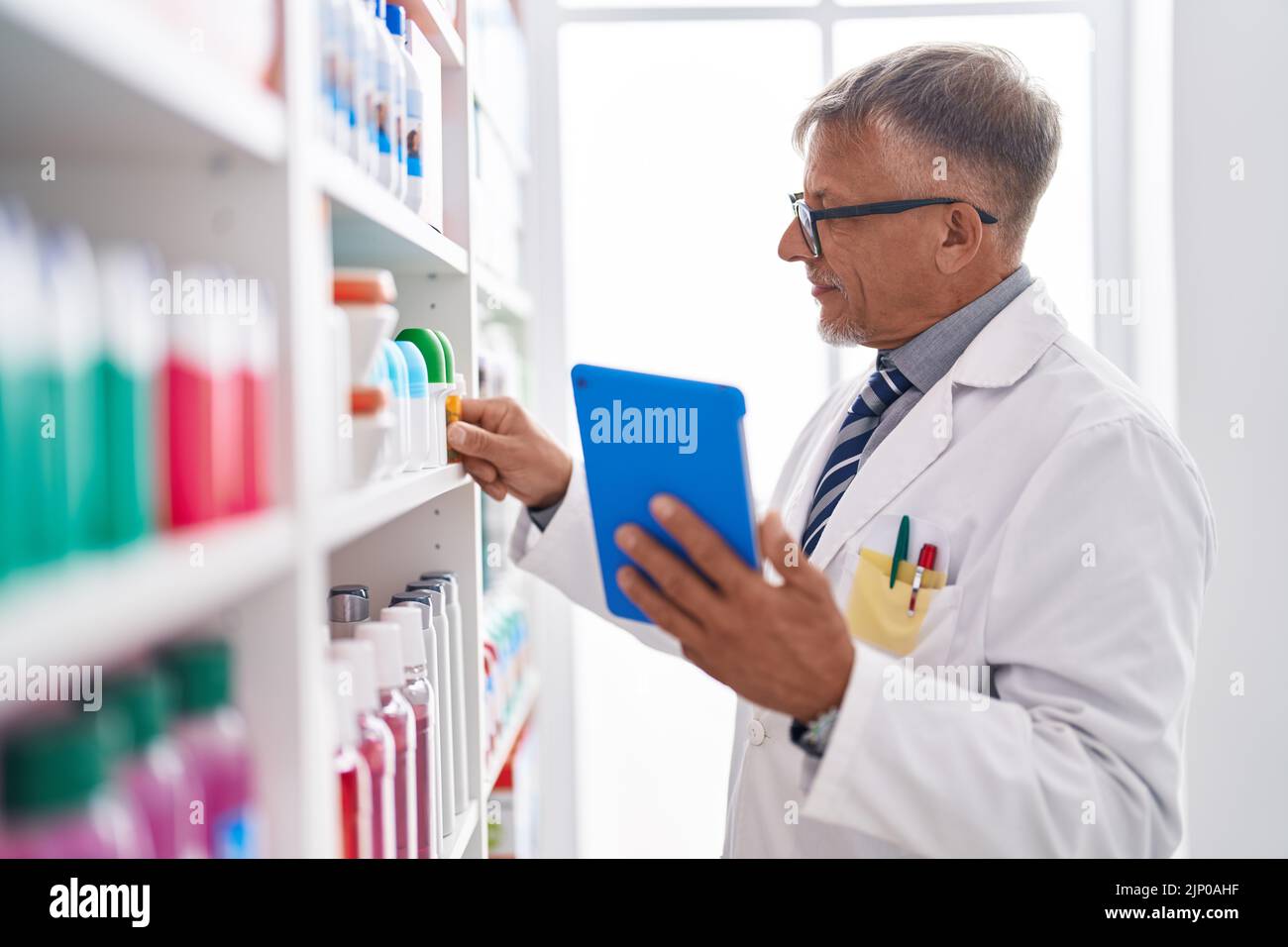 Middle age grey-haired man pharmacist using touchpad working at laboratory Stock Photo - Alamy