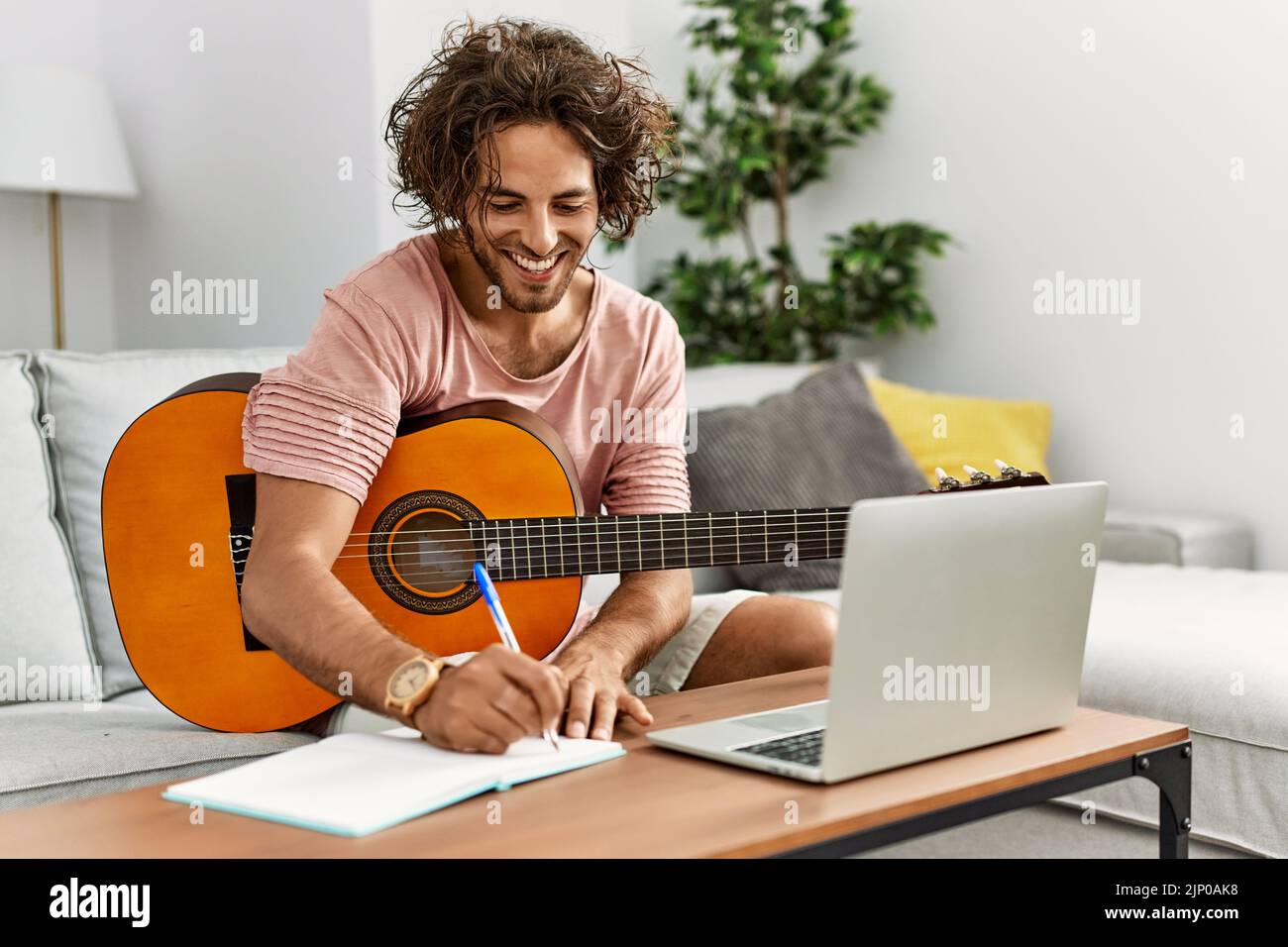 Young hispanic composer man composing song using guitar and laptop at ...
