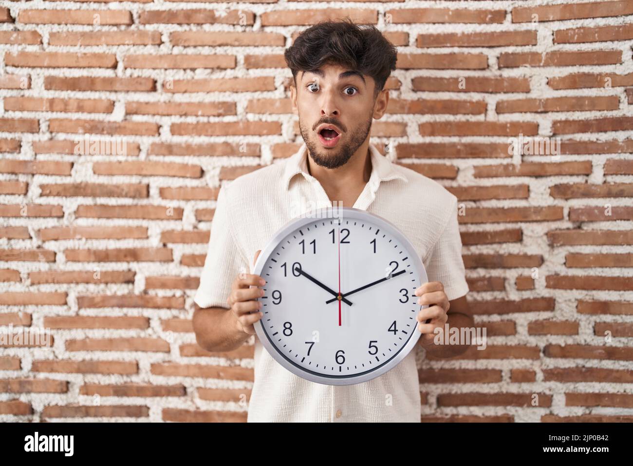 Arab man with beard holding big clock in shock face, looking skeptical ...