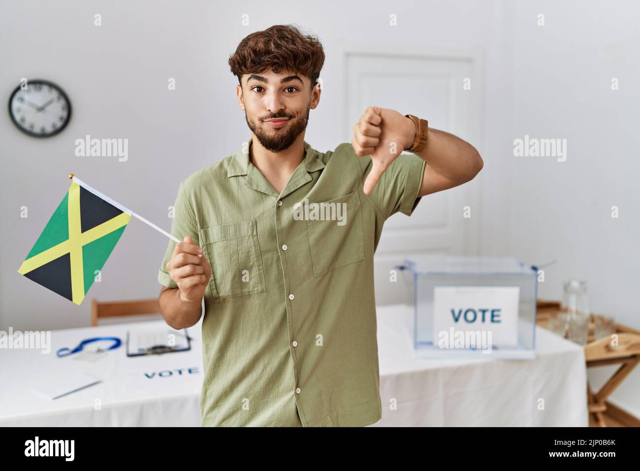Young arab man at political campaign election holding jamaica flag with ...