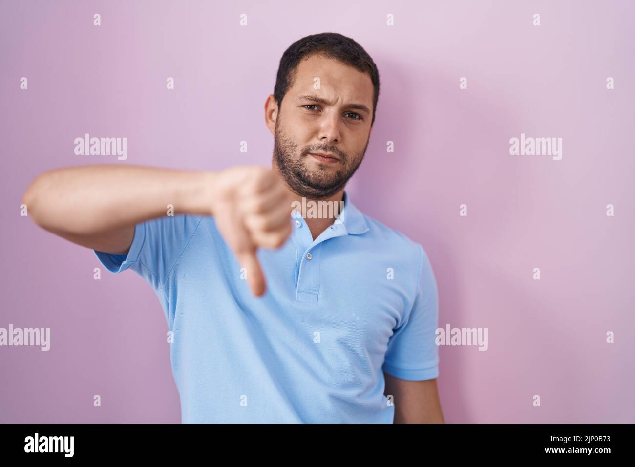 Hispanic man standing over pink background looking unhappy and angry ...