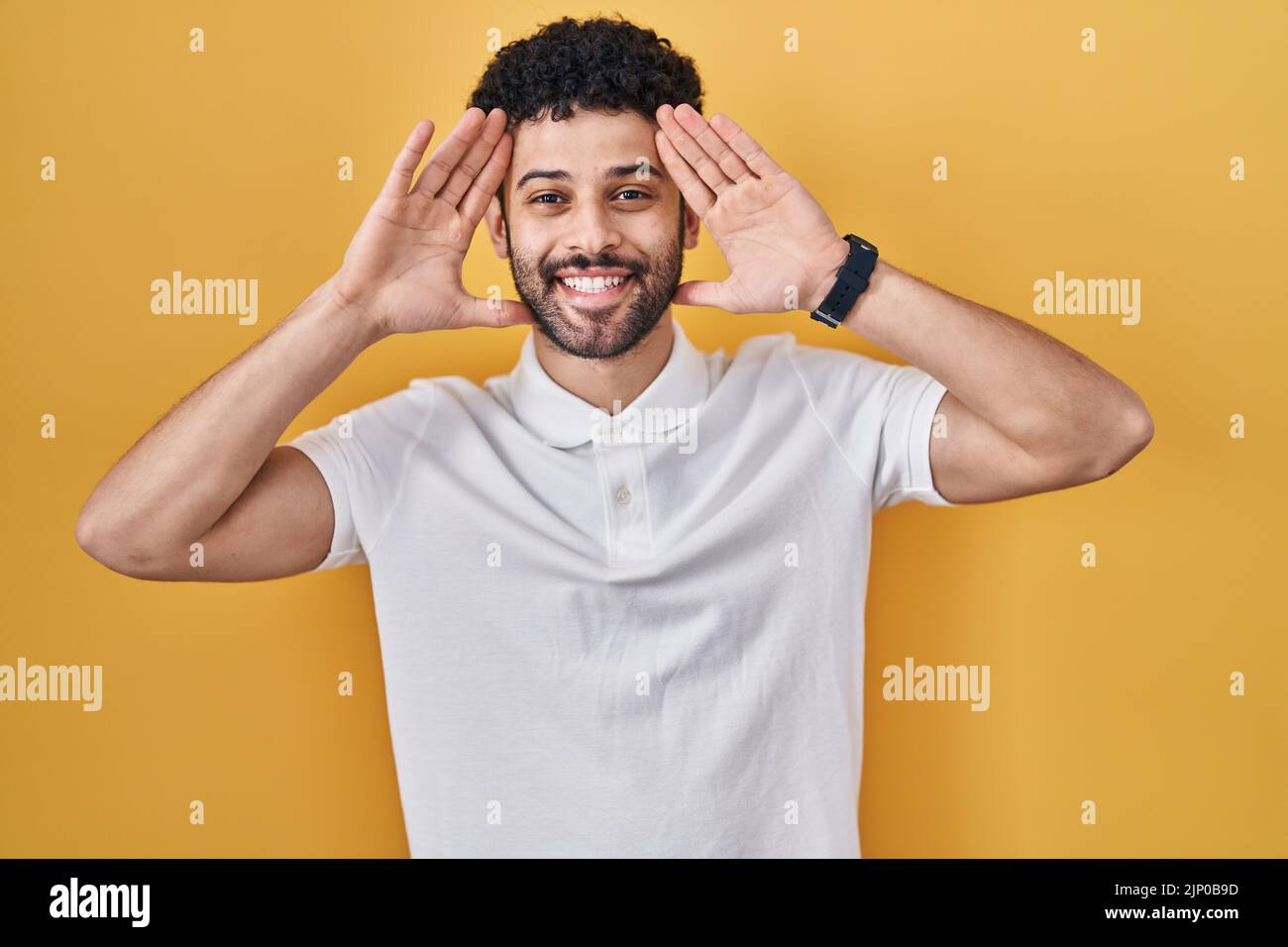 Arab man standing over yellow background smiling cheerful playing peek ...