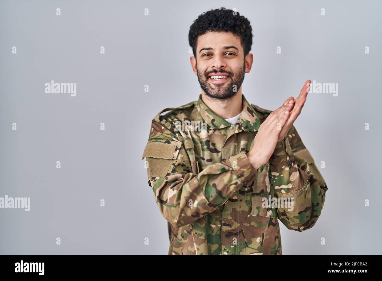 Arab man wearing camouflage army uniform clapping and applauding happy ...