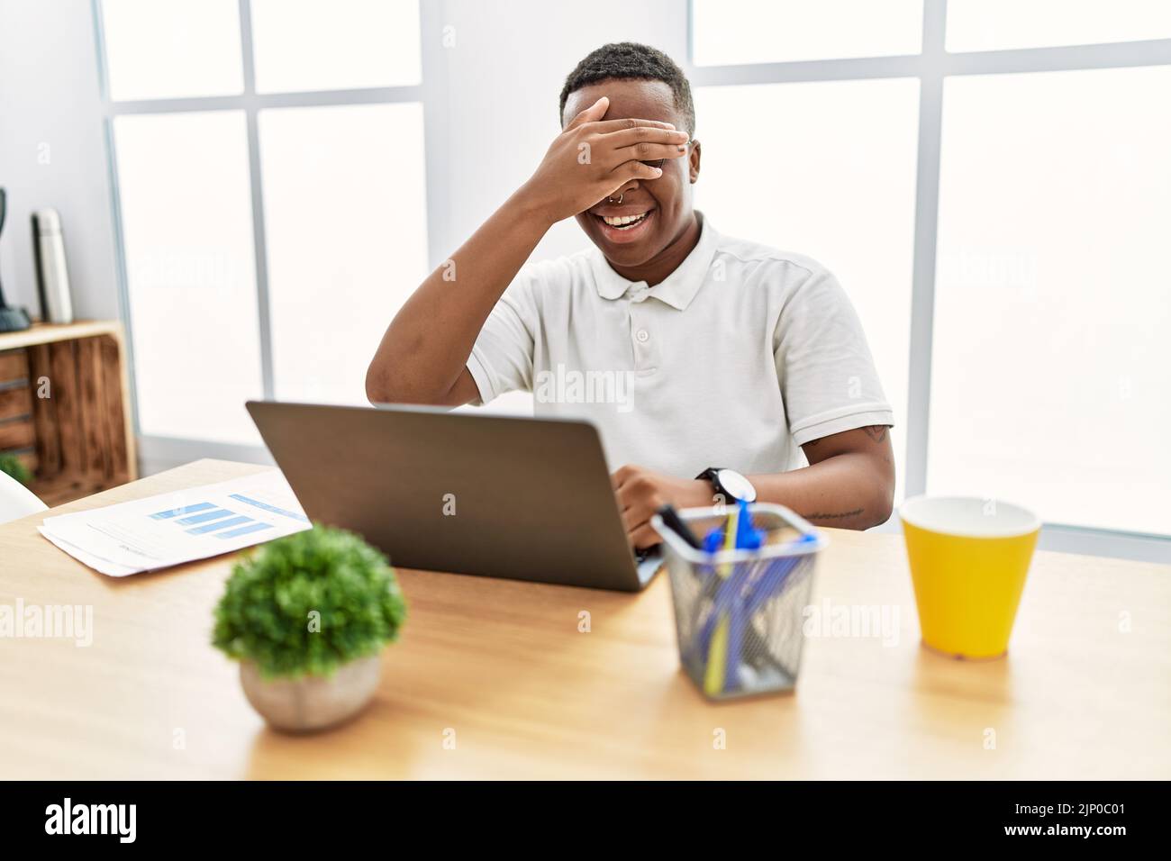 Young african man working at the office using computer laptop smiling ...