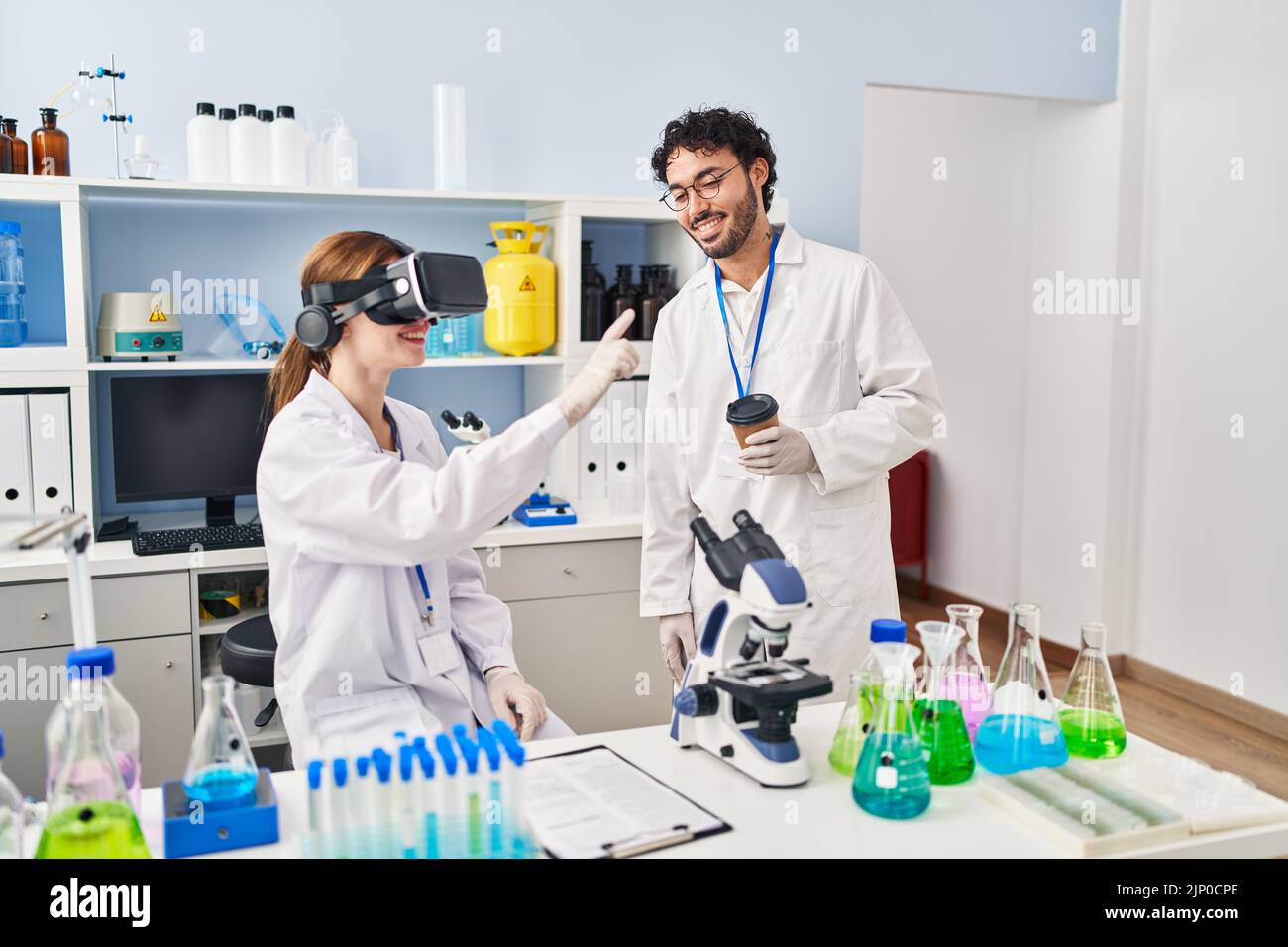 Man and woman scientist partners using vr goggles and drinking coffee ...