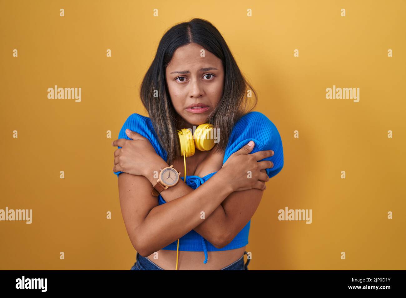 Hispanic young woman standing over yellow background shaking and ... Hispanic young woman standing over yellow background shaking and ...