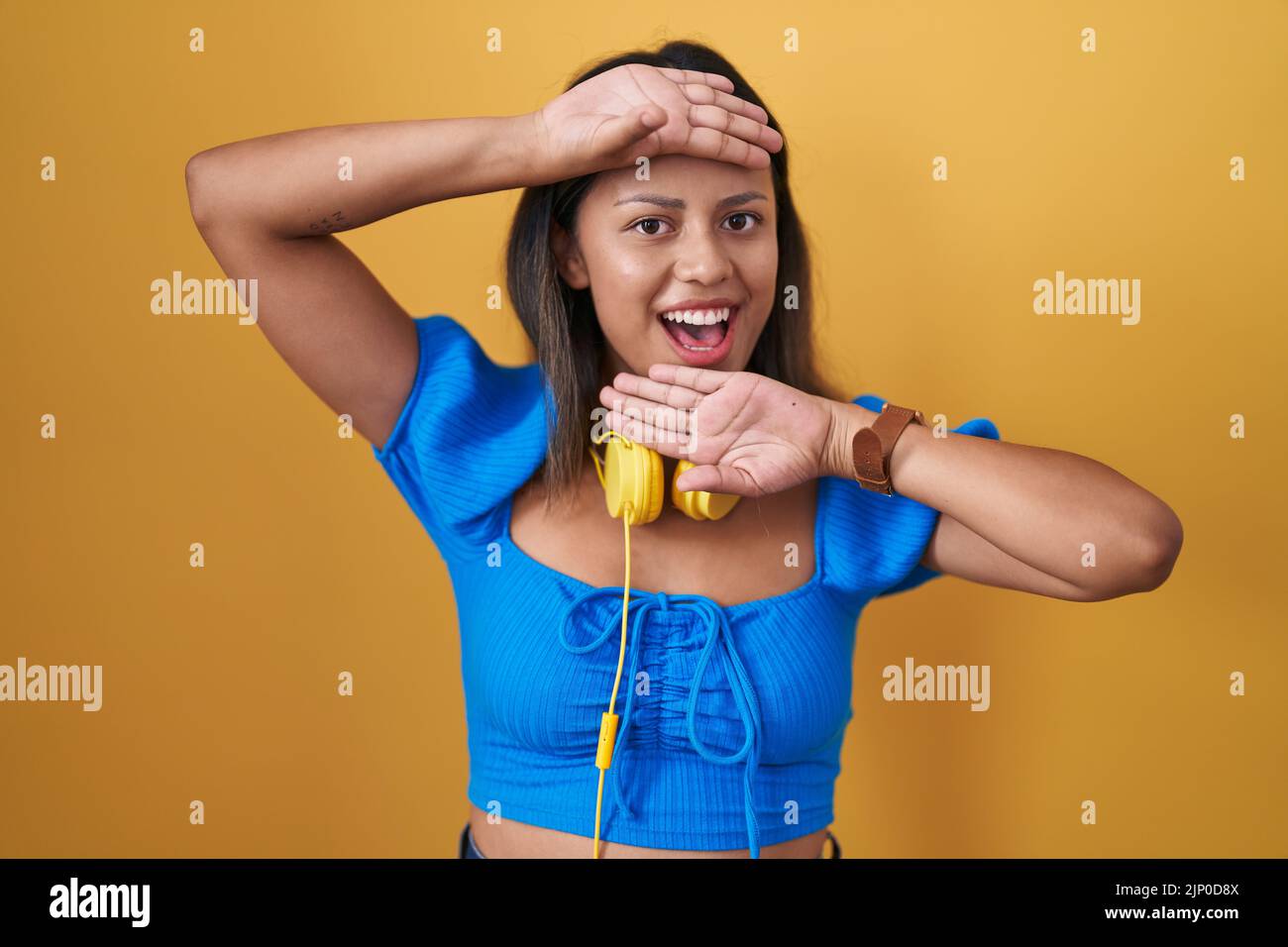 Hispanic young woman standing over yellow background smiling cheerful ...
