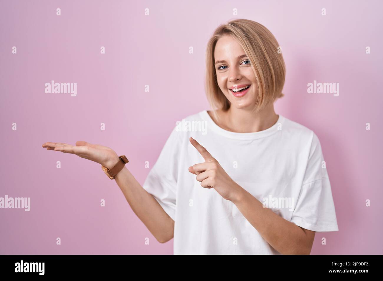 Young caucasian woman standing over pink background amazed and smiling ...