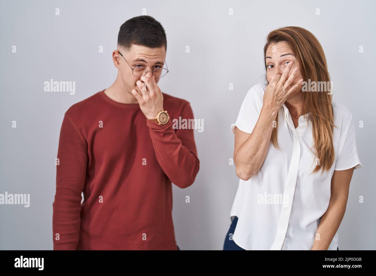 Mother and son standing together over isolated background smelling ...