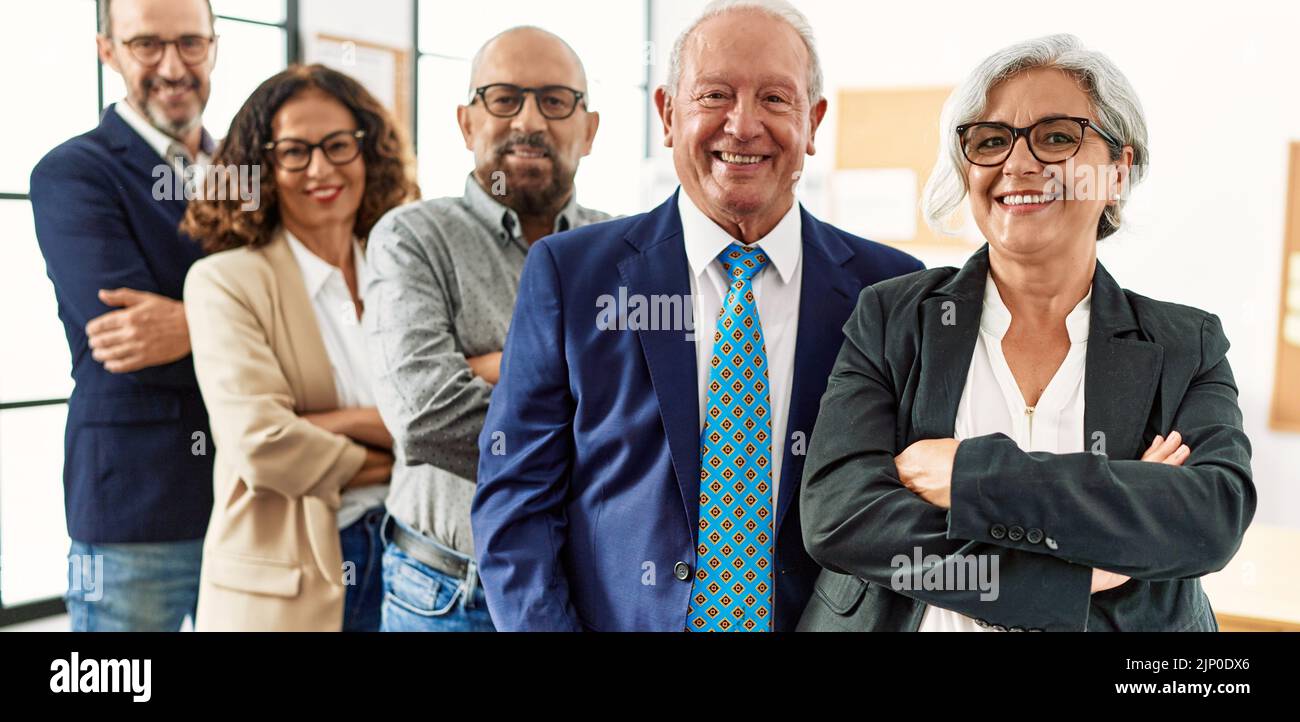 Group of middle age business workers smiling happy standing with arms ...