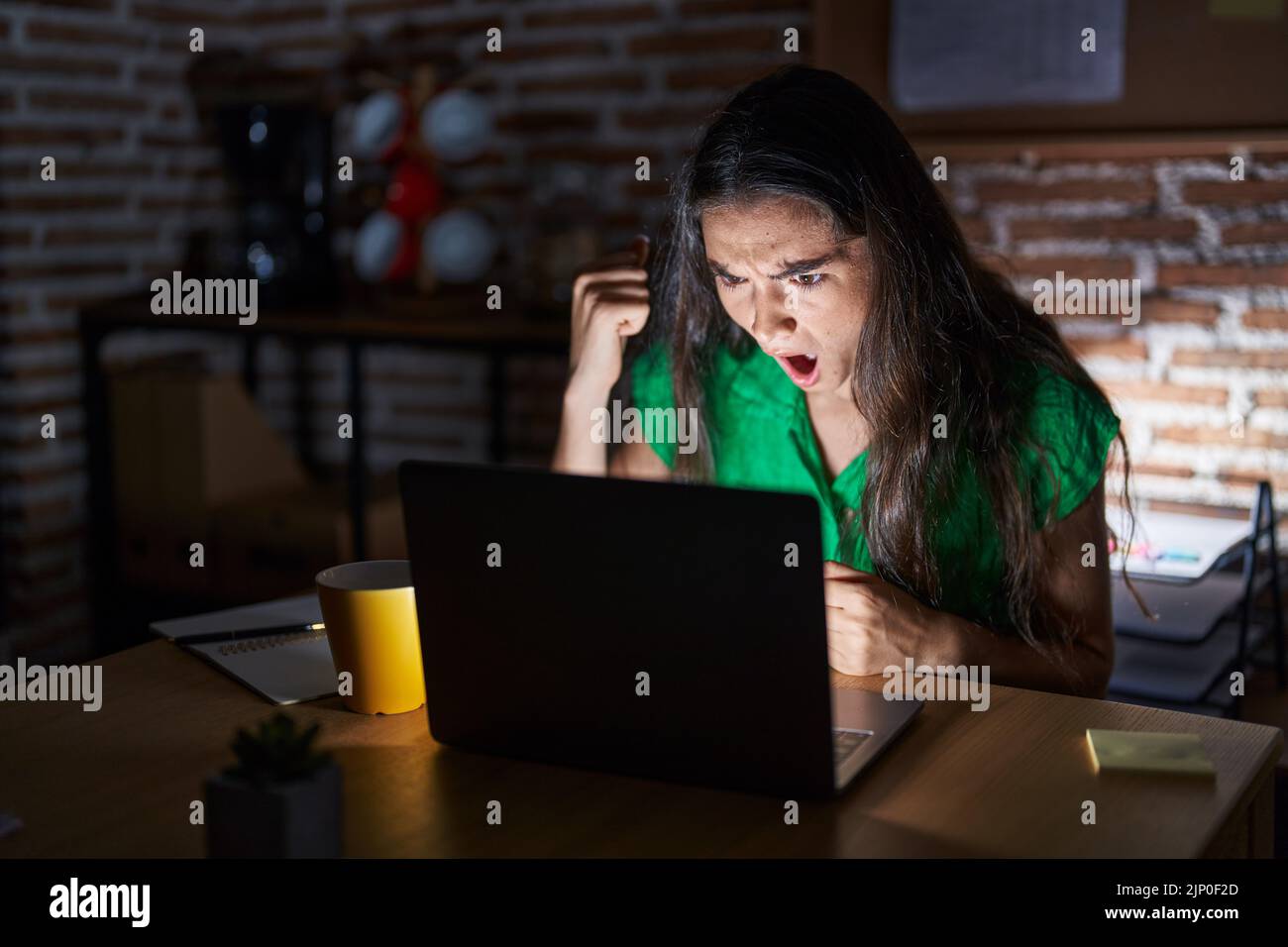 Young teenager girl working at the office at night angry and mad ...
