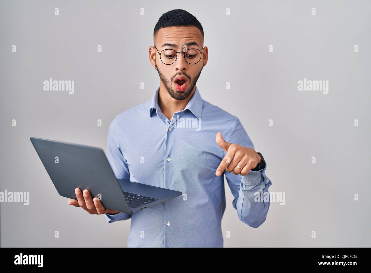 Young hispanic man working using computer laptop pointing down with ...