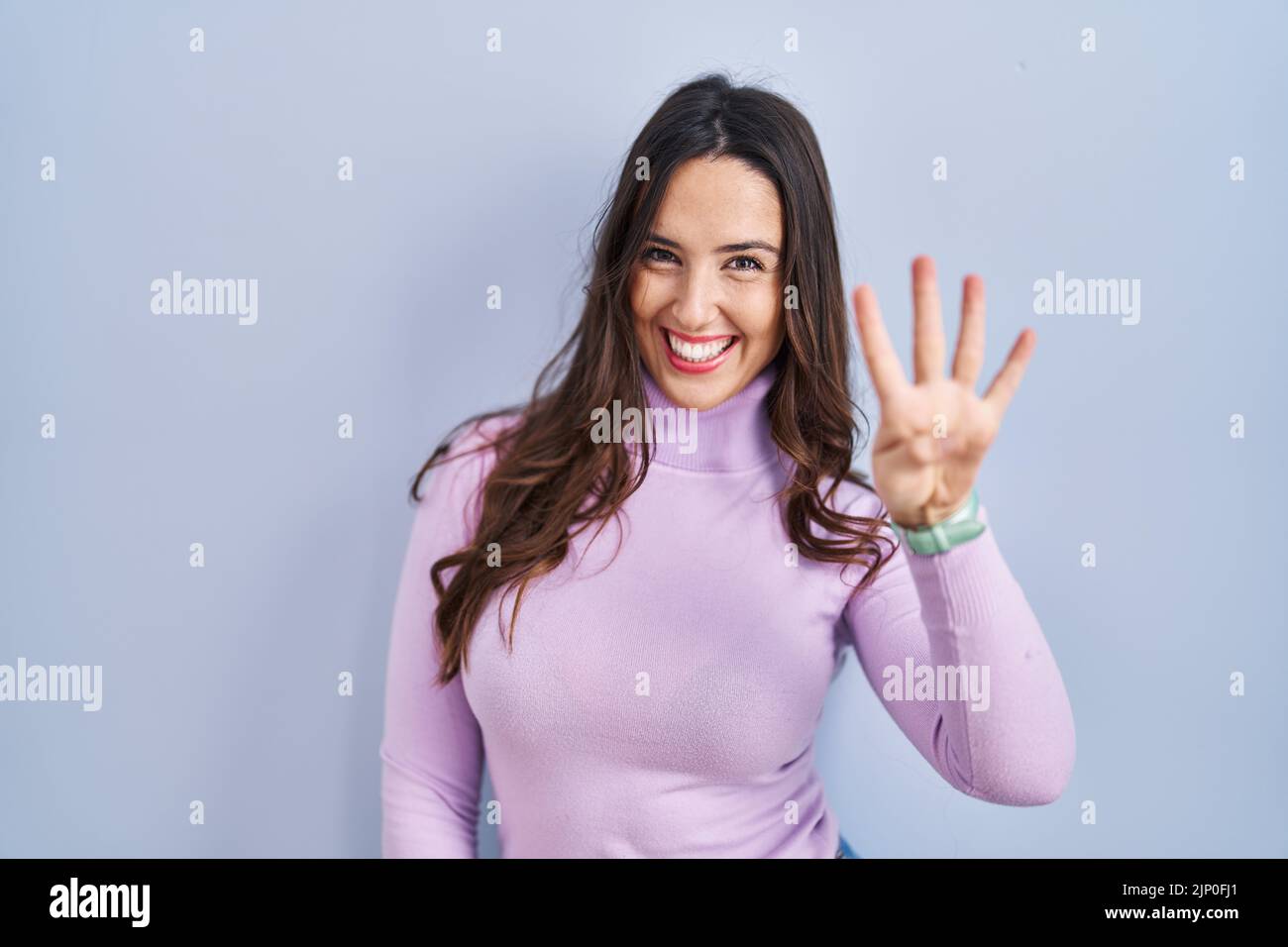 Young brunette woman standing over blue background showing and pointing ...