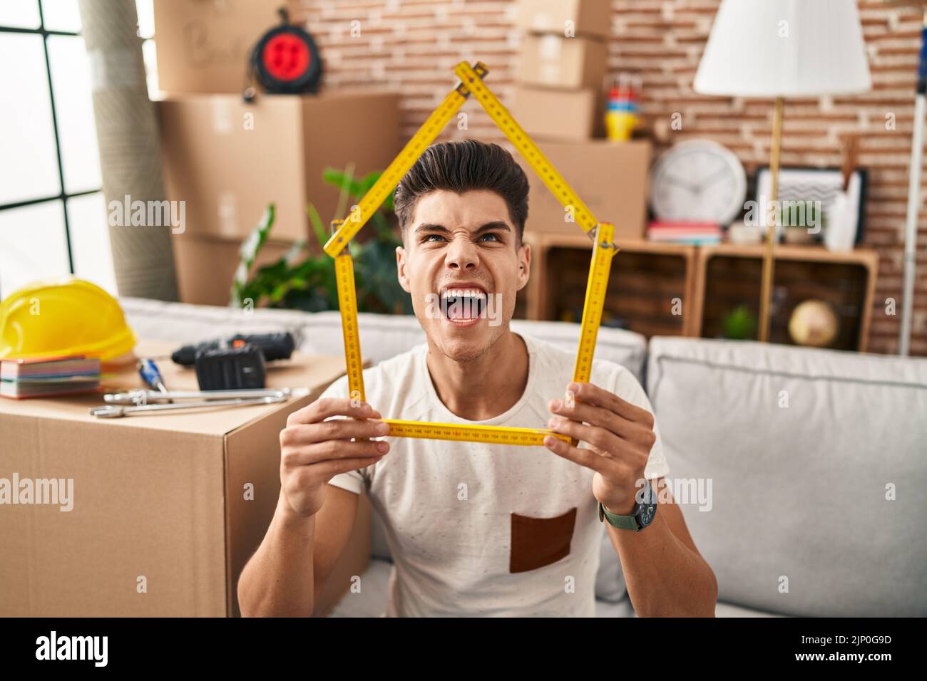 Young hispanic man moving to a new home angry and mad screaming ...