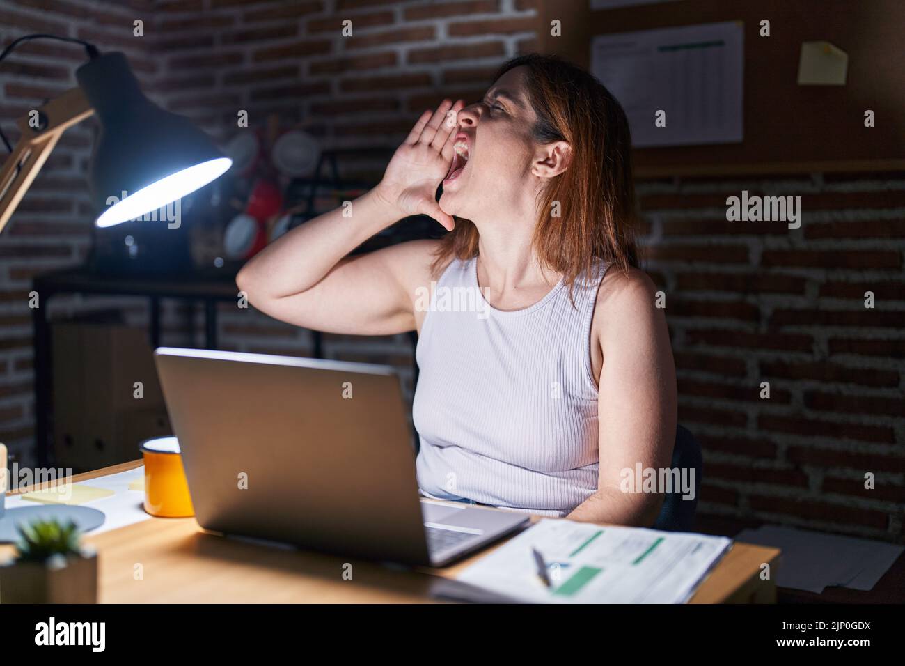 Brunette woman working at the office at night shouting and screaming ...