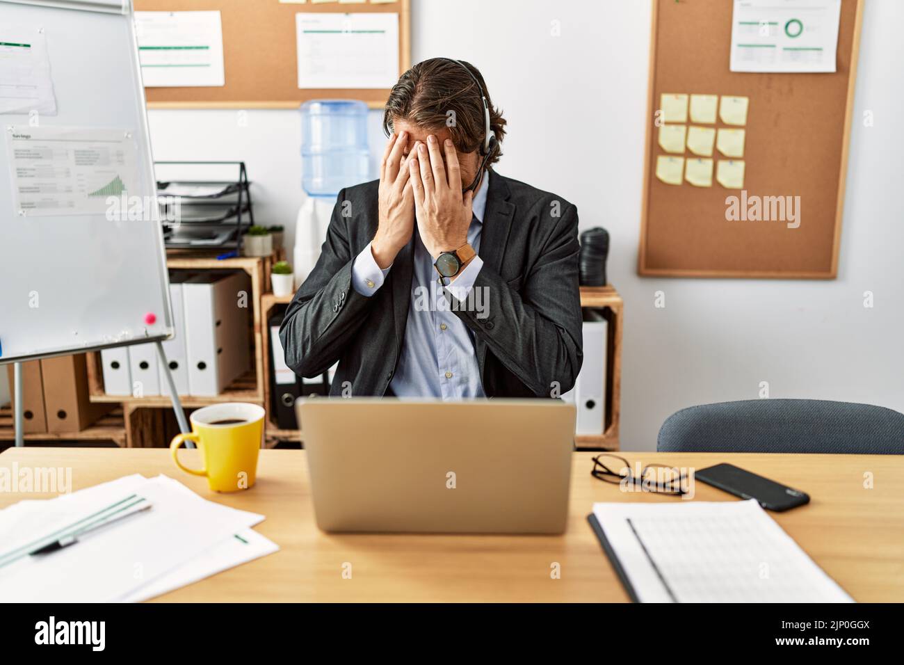 Handsome middle age man wearing call center agent headset at the office ...
