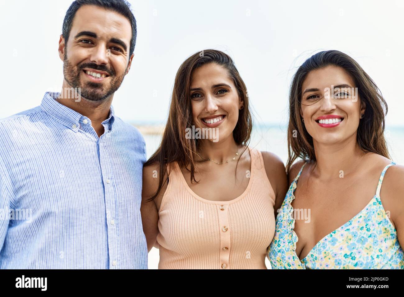 Three young hispanic friends smiling happy and hugging at the beach ...