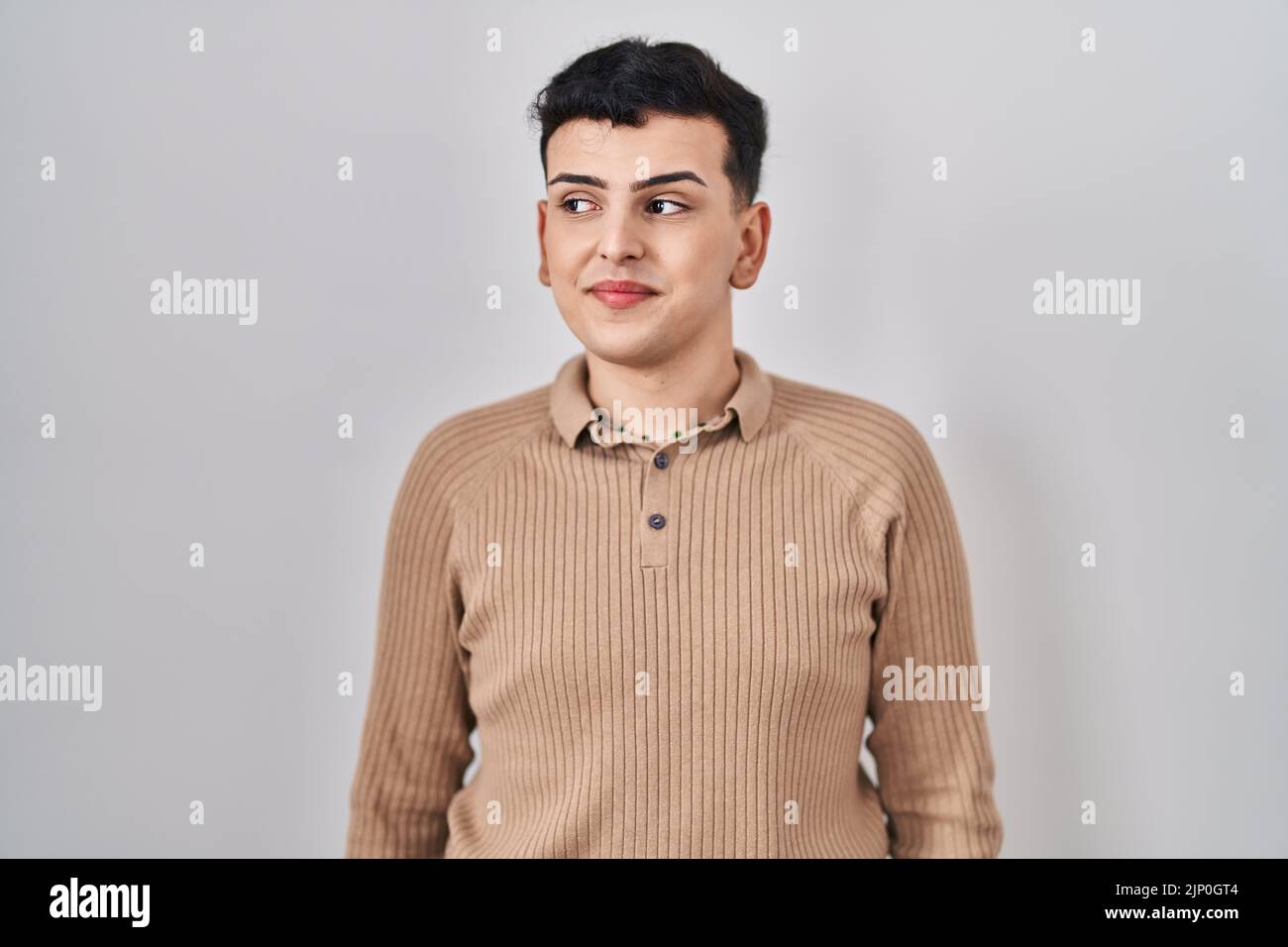Non binary person standing over isolated background smiling looking to ...