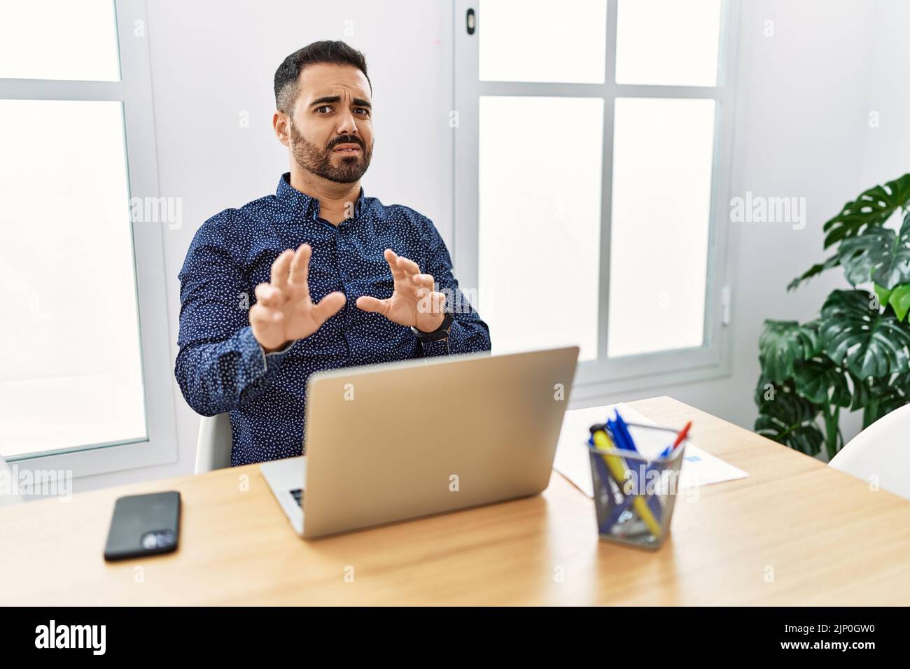 Young hispanic man with beard working at the office with laptop ...