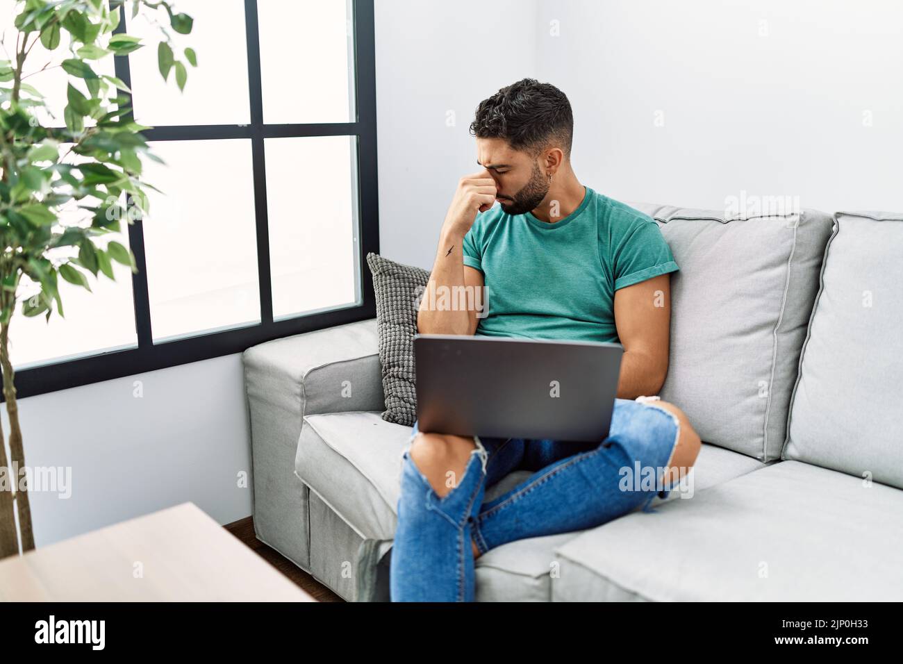 Young handsome man with beard using computer laptop sitting on the sofa ...