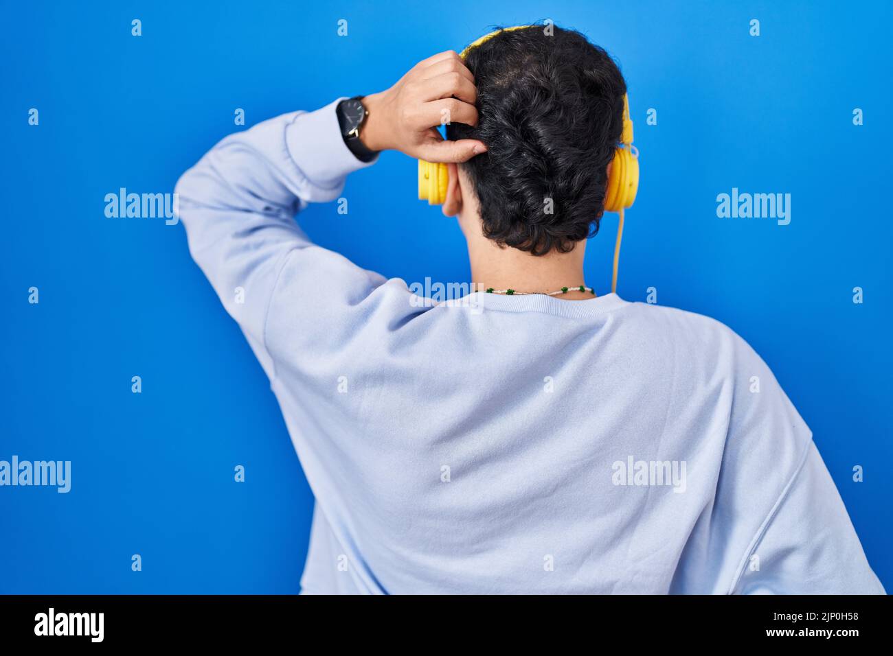 Non binary person listening to music using headphones backwards ...