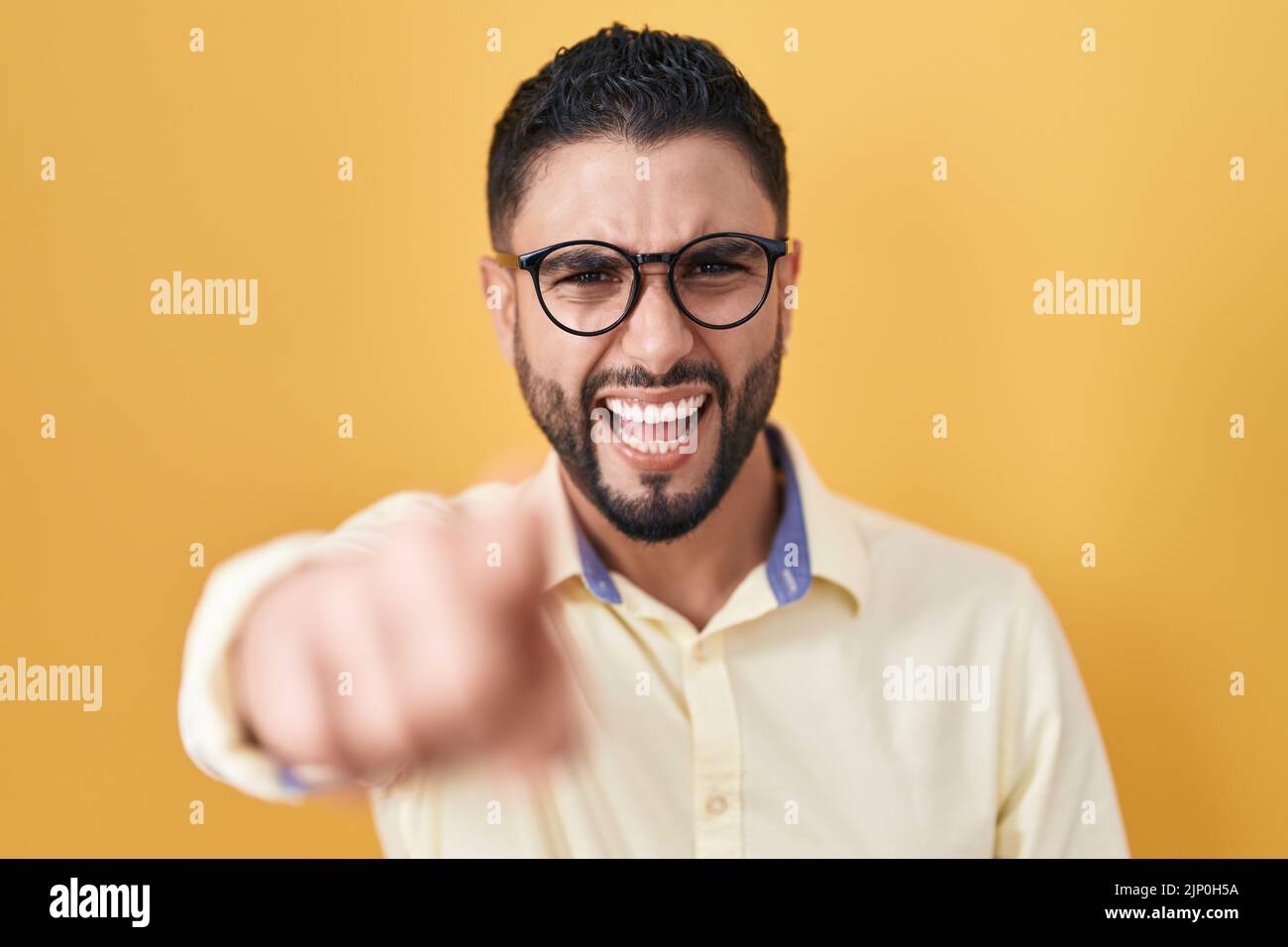 Hispanic young man wearing business clothes and glasses pointing ...