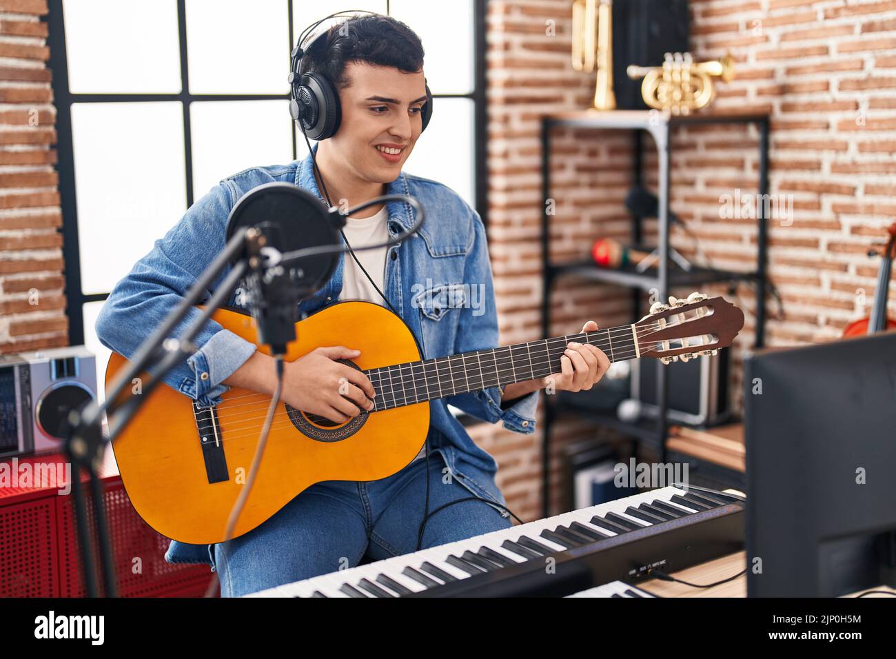 Young non binary man musician singing song playing classical guitar at ...