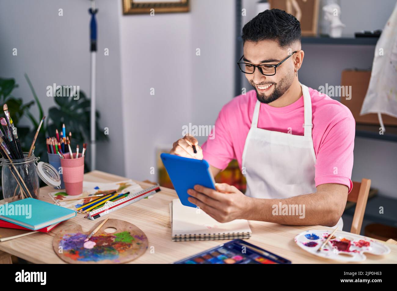 Young arab man artist drawing on notebook using touchpad at art studio ...