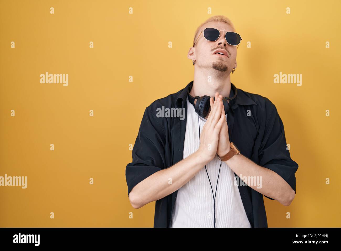 Young caucasian man wearing sunglasses standing over yellow background ...